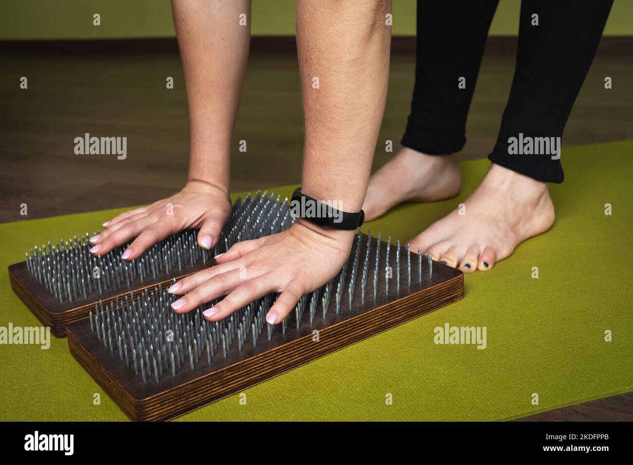 A woman practicing yoga, performs exercises on a sadhu board with nails ...