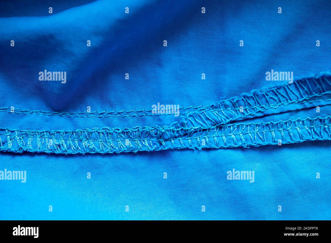 Overlock seam on blue fabric. Textured cloth background. Place for text ...