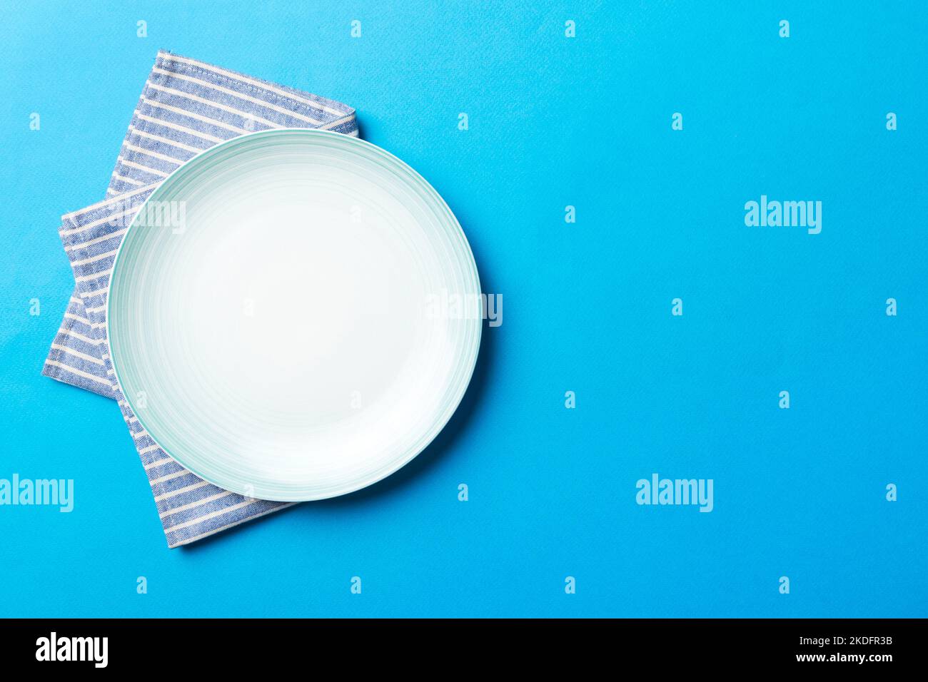 Top view on colored background empty round Blue plate on tablecloth for ...