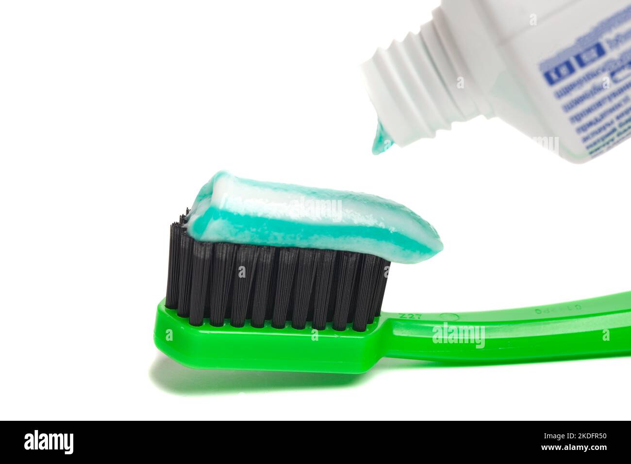 Close up of squeezing toothpaste on toothbrush on white background ...
