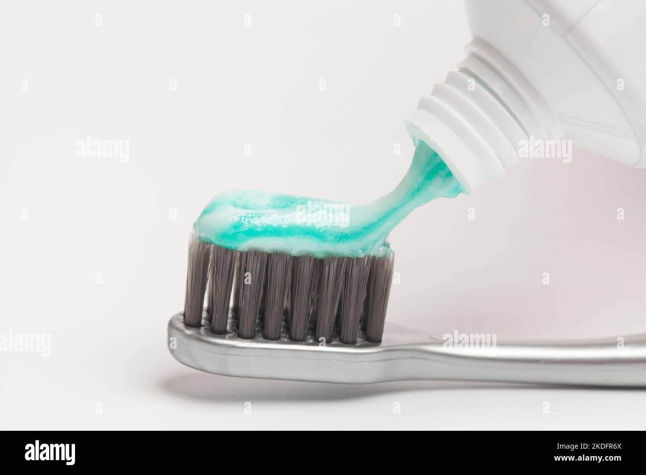 Close up of squeezing toothpaste on toothbrush on white background ...