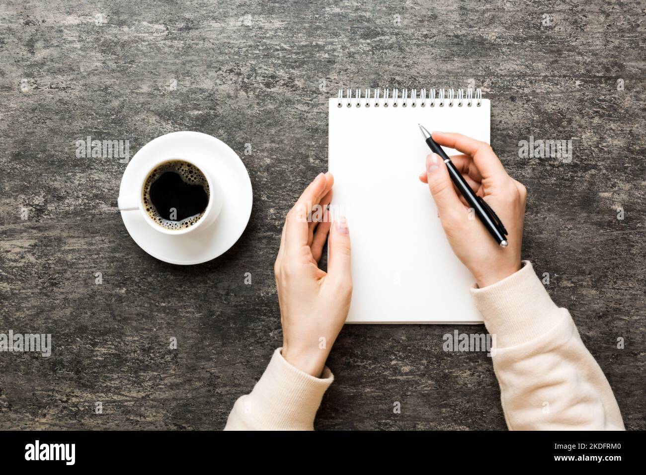 Woman hand with pencil writing on notebook and hold coffee cup. Woman ...