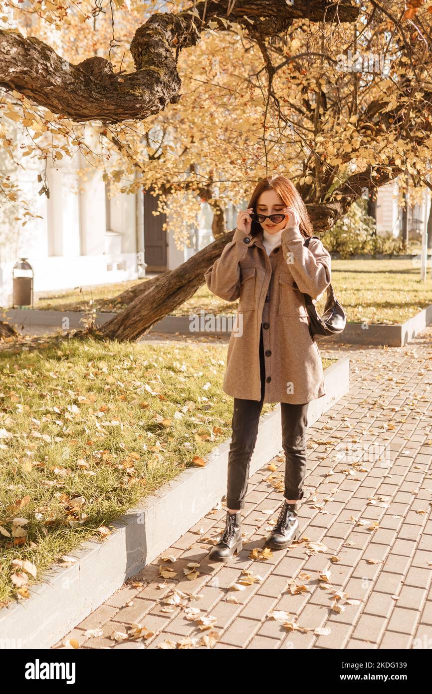 A stylish brunette woman walks around the autumn city. The season is ...