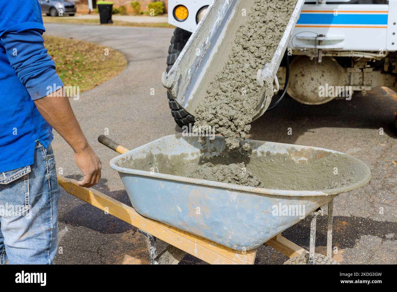 Mixer truck pours concrete into wheelbarrow at construction site Stock ...