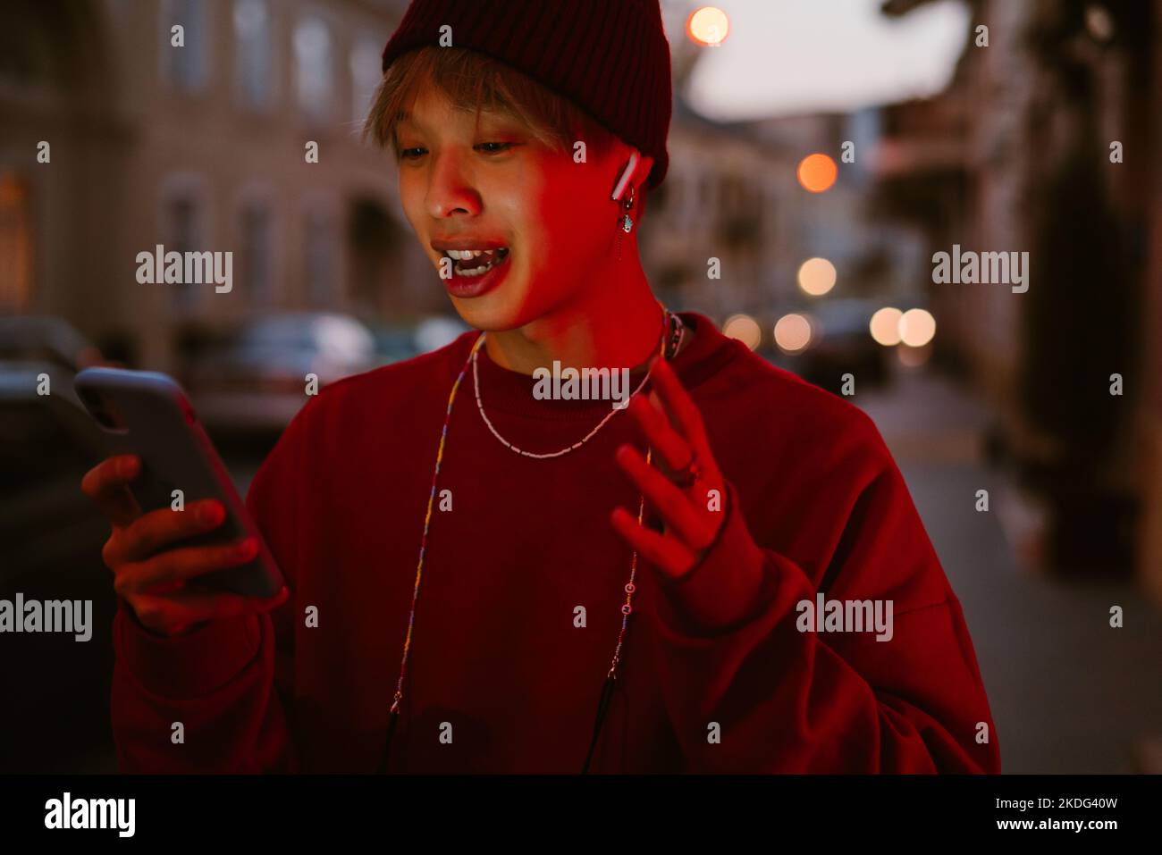 Asian boy gesturing while making video call on cellphone at city street ...