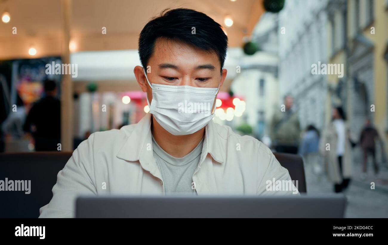 Smiling man in protective mask look at laptop screen chatting remote ...