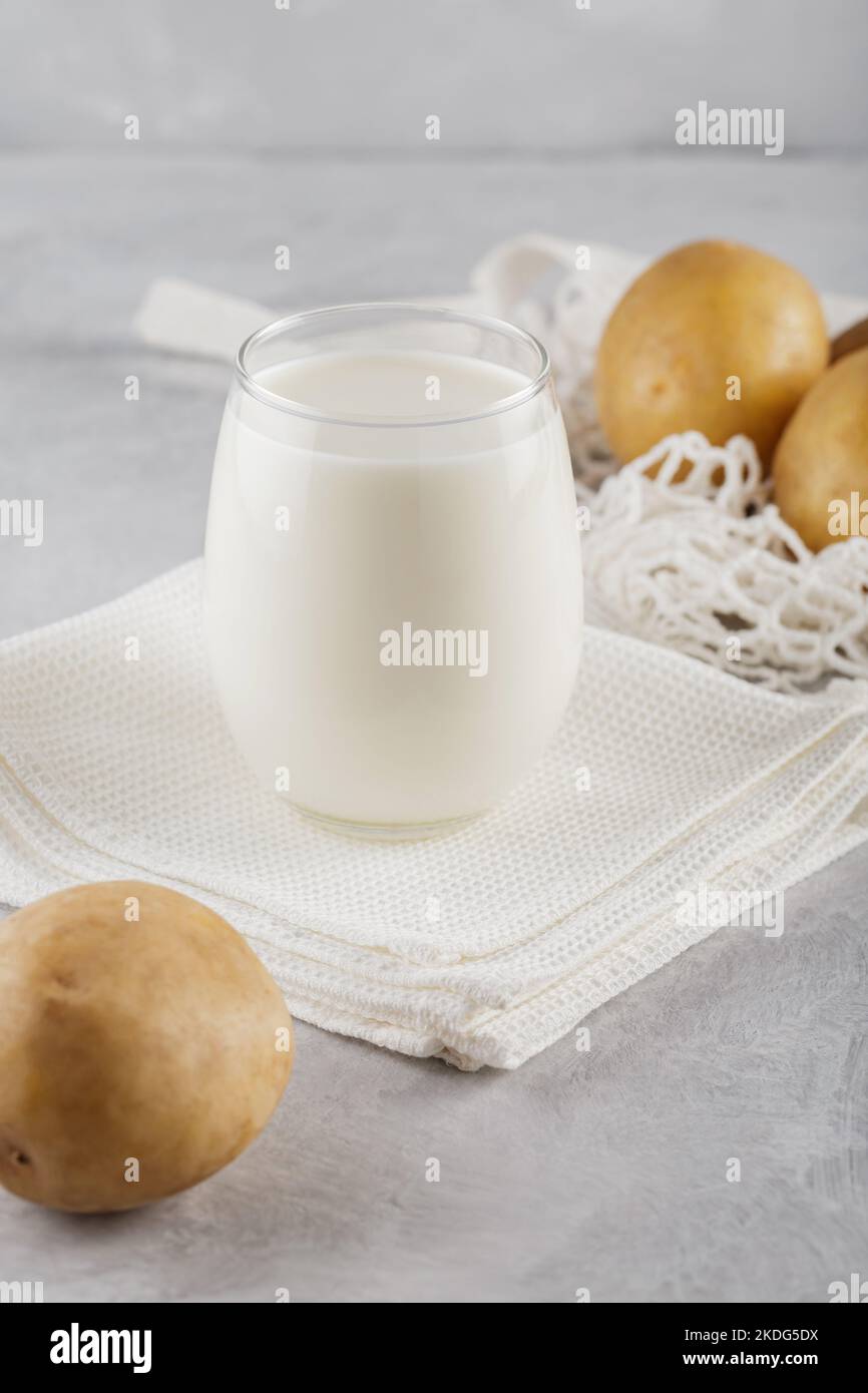 Potato milk and raw potatoes in a mesh bag. Plant based milk replacer ...