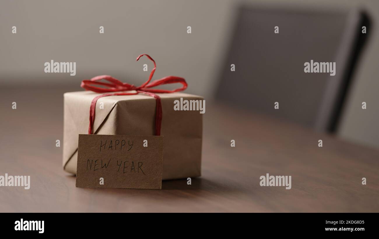 brown paper gift box with red bow on wood table with paper card, wide ...