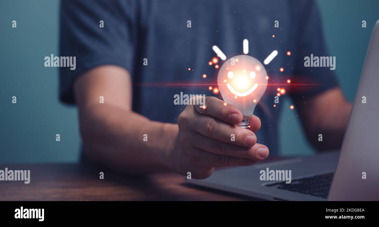 Hand of a man holding a light bulb with happy smile face and using a ...