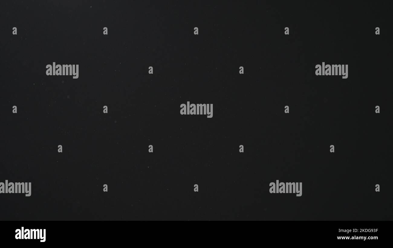 Dust particles float in neutral light on black background, wide photo ...