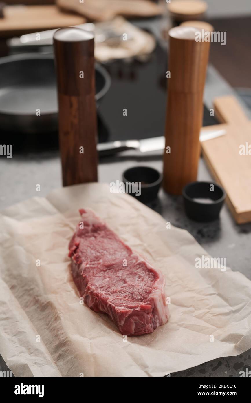 Raw new york sirloin steak on parchment paper warming up before cooking ...