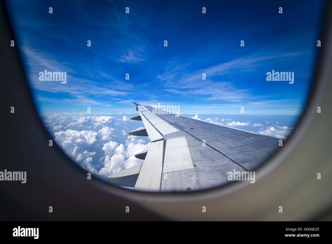 Wing of an airplane flying above the clouds look from cabin window ...