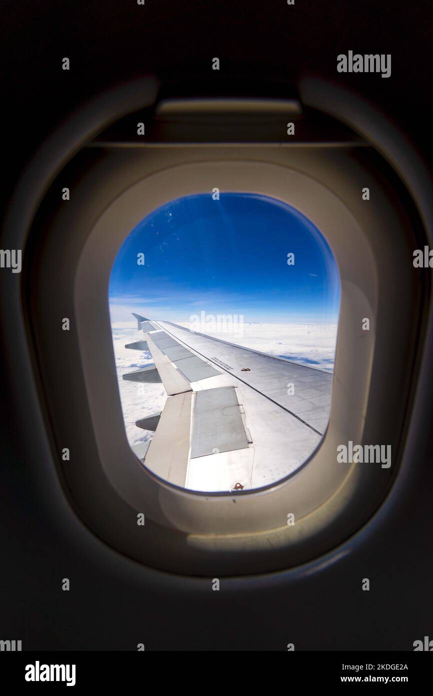 Wing of an airplane flying above the clouds look from cabin window ...
