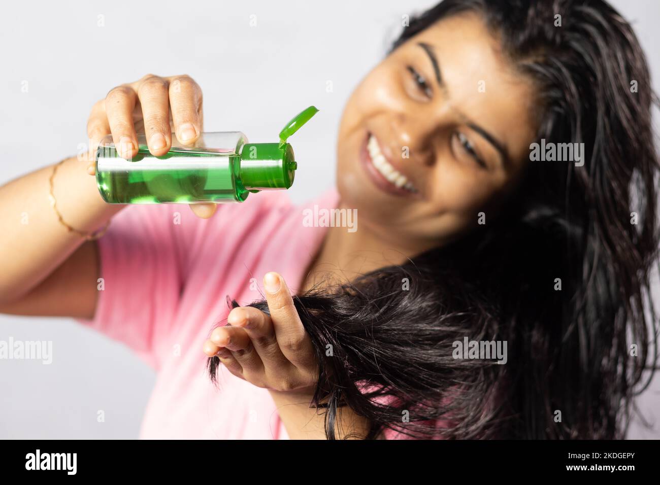 Selective focus on hair oil being applied by a beautiful indian woman ...