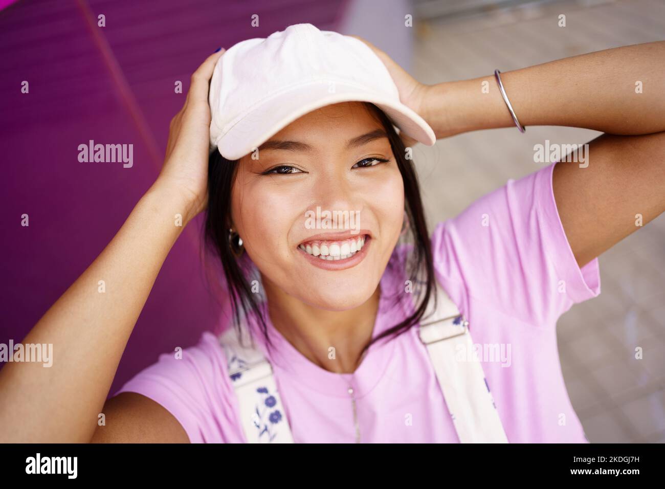 Asian woman touching head and smiling Stock Photo - Alamy