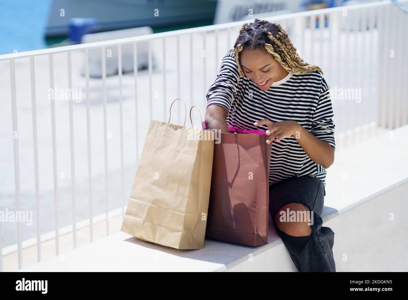 Black woman looking for something in her shopping bags in a shopping ...