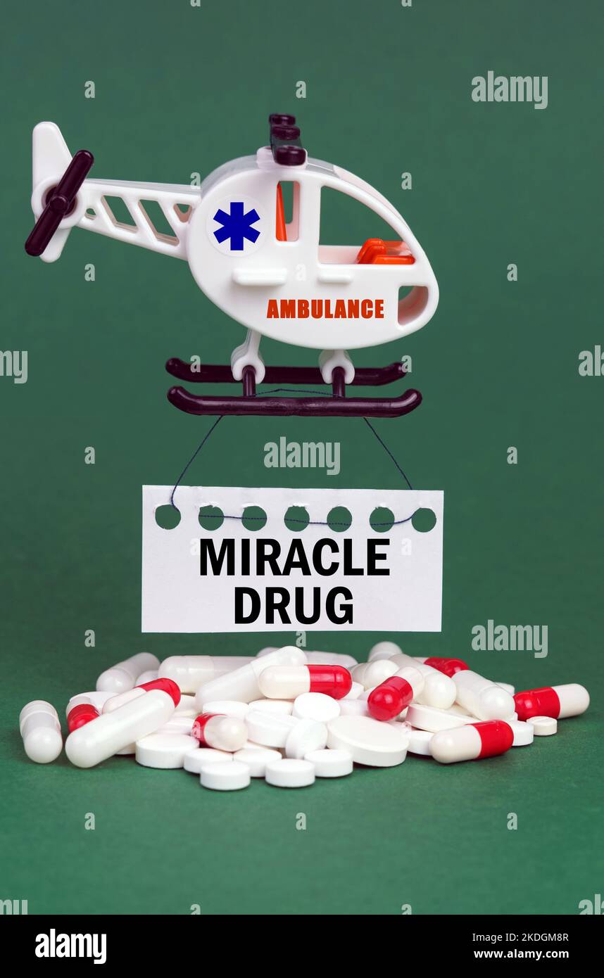 Medical concept. On a green surface, an ambulance helicopter, pills and ...
