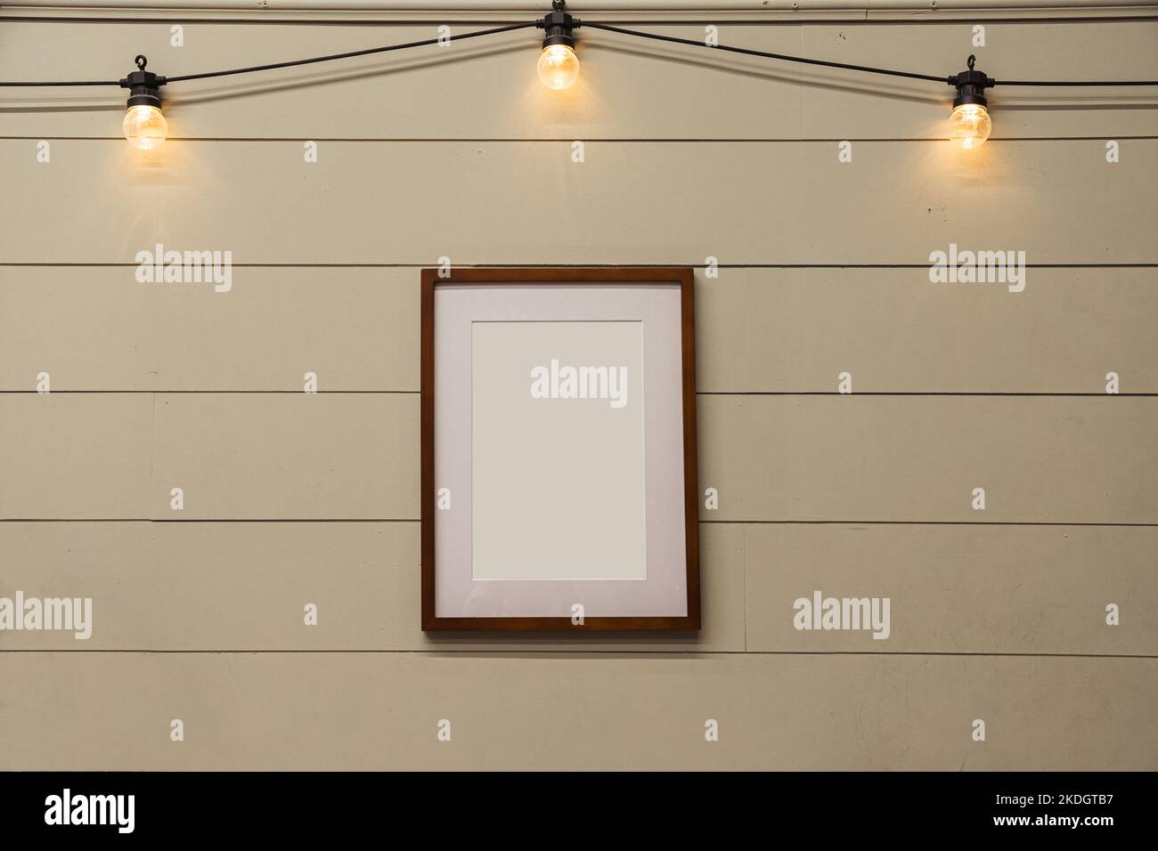 Empty, blank wooden frame on wooden wall with garland and light bulbs ...