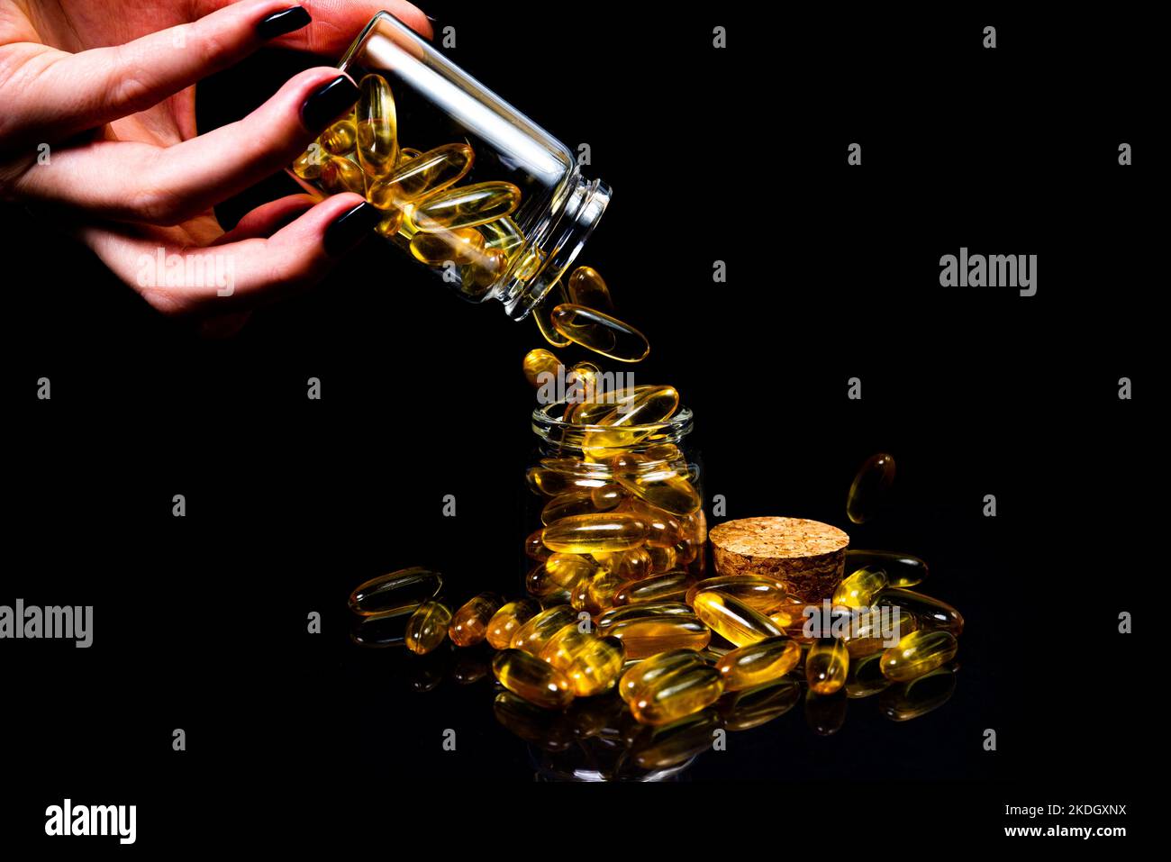 Fish oil capsules. Yellow omega 3 pills in jar on the dark black. fish ...