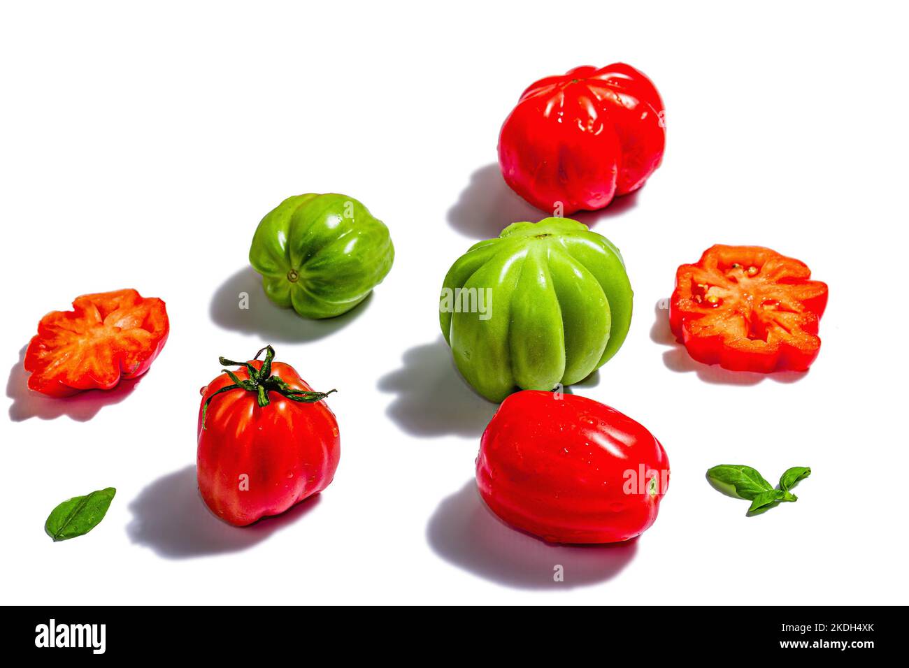Green and red ribbed tomatoes isolated on white background. American or ...