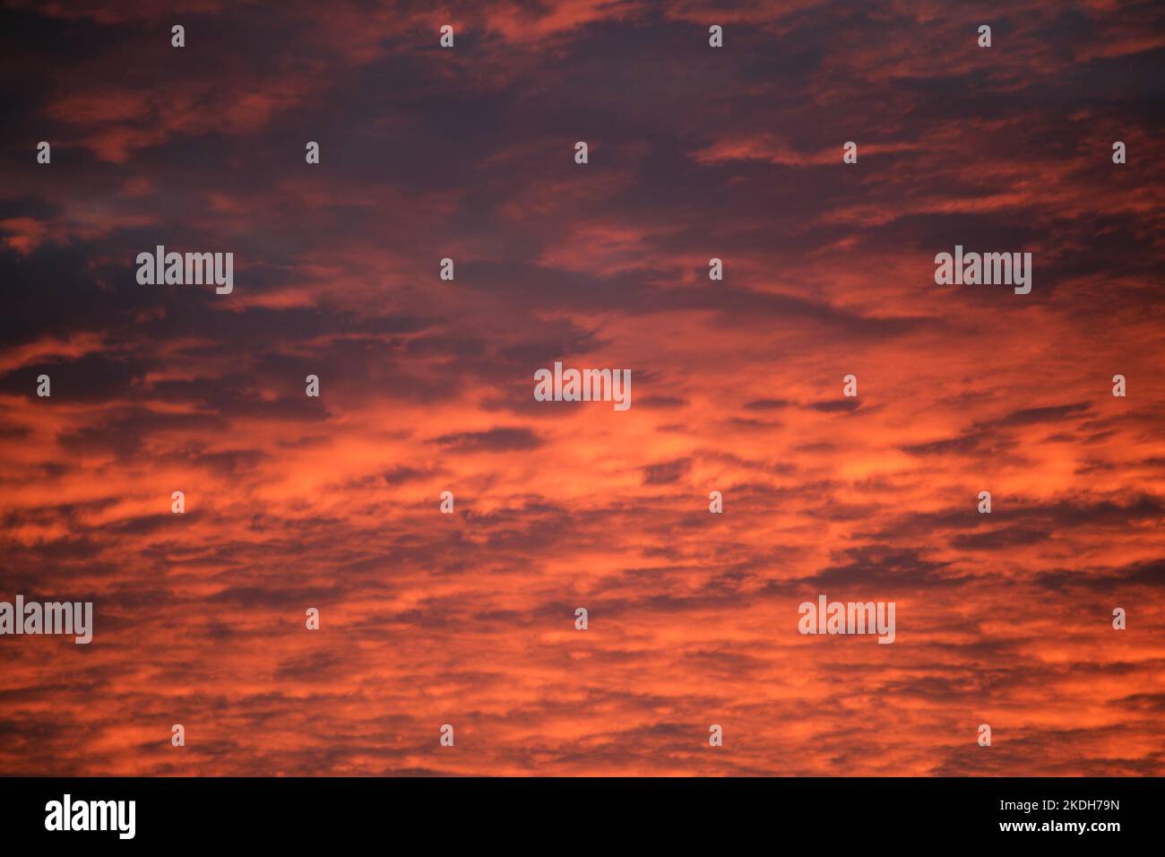 Bright colorful sunset sky with vivid smooth clouds illuminated with setting sun light spreading ...