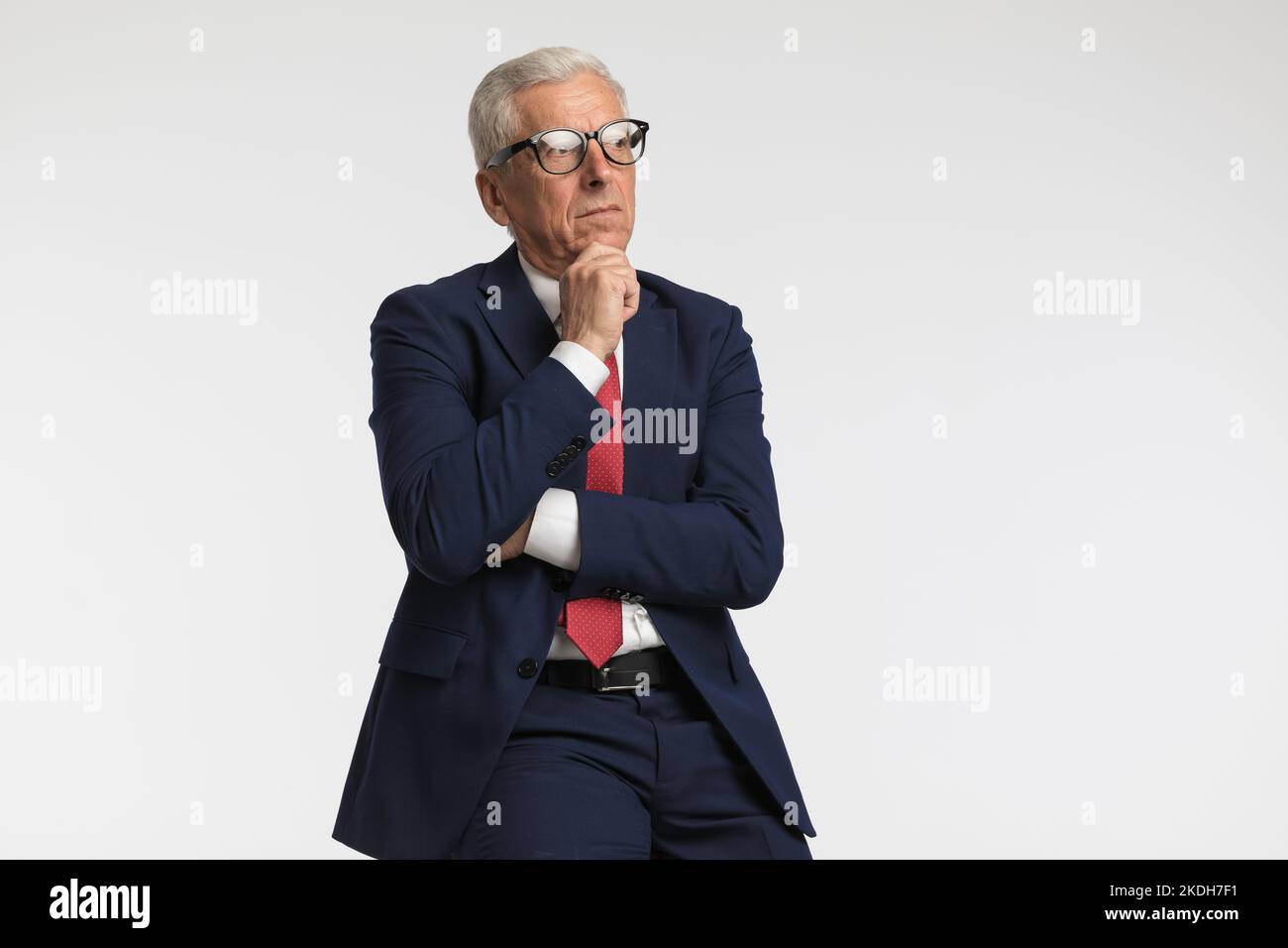 Old businessman looking away, scratching his chin and thinking about ...