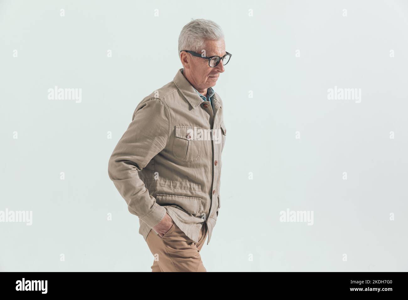 old casual man walking with hands in pockets and looking down, feeling ...