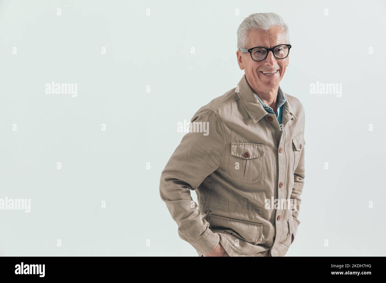 happy casual man smiling warmly, holding his hands in pockets and ...