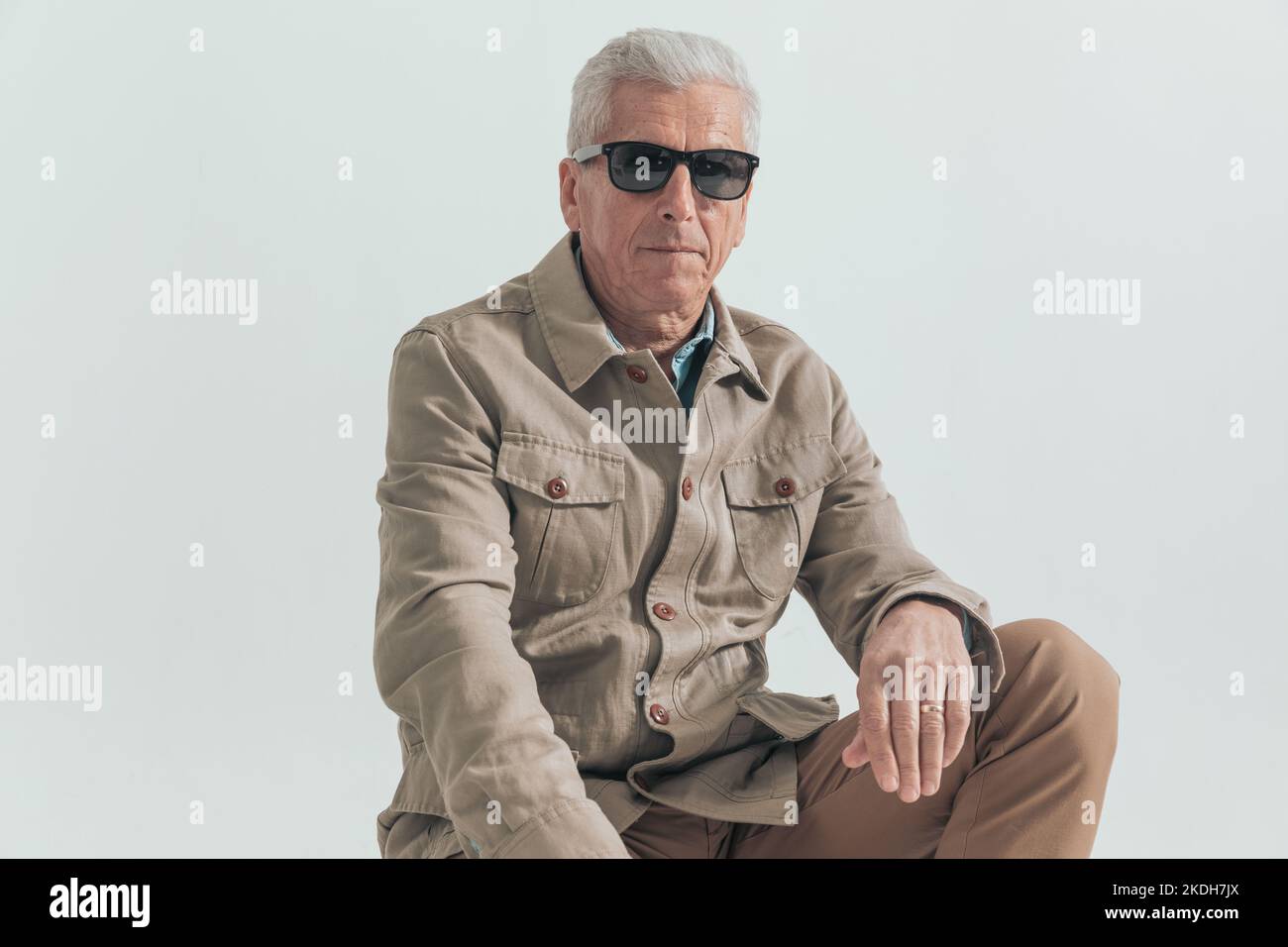 Cool business man in his 60s wearing sunglasses, resting his hands on ...