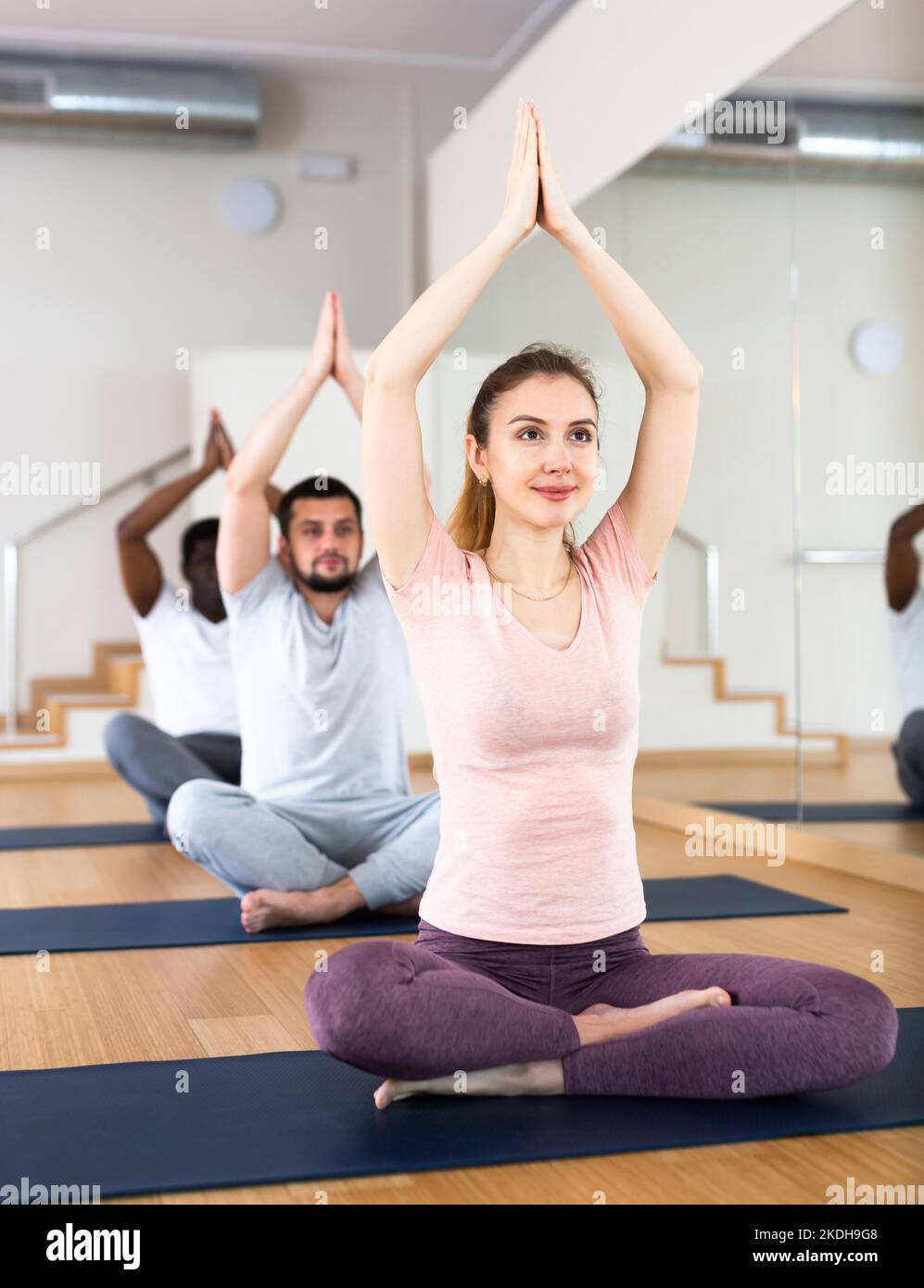Woman sitting in Padmasana yoga position with arms in namaste above ...