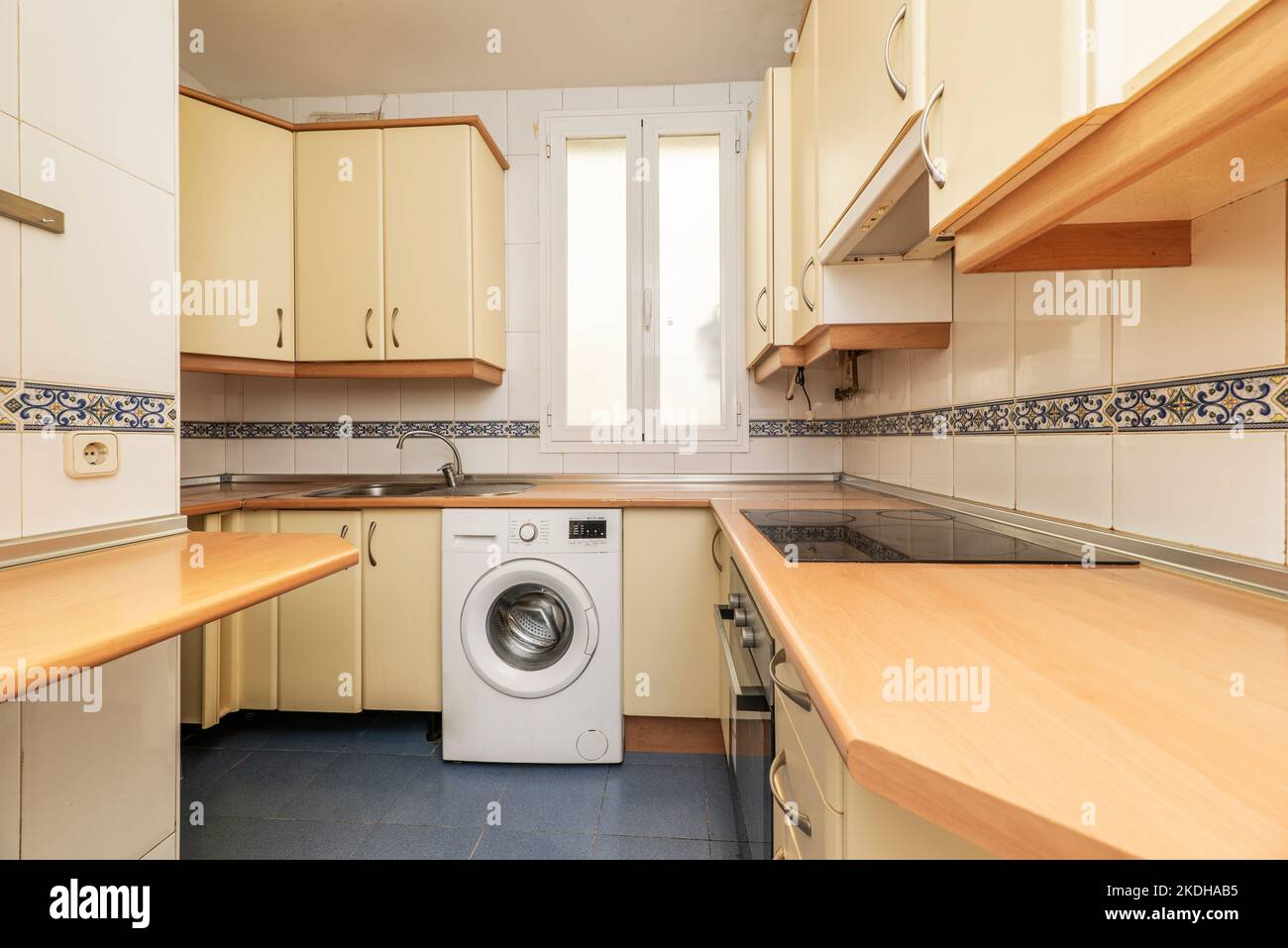 Kitchen with cream-colored wood cabinets, wood-colored countertop, and ...