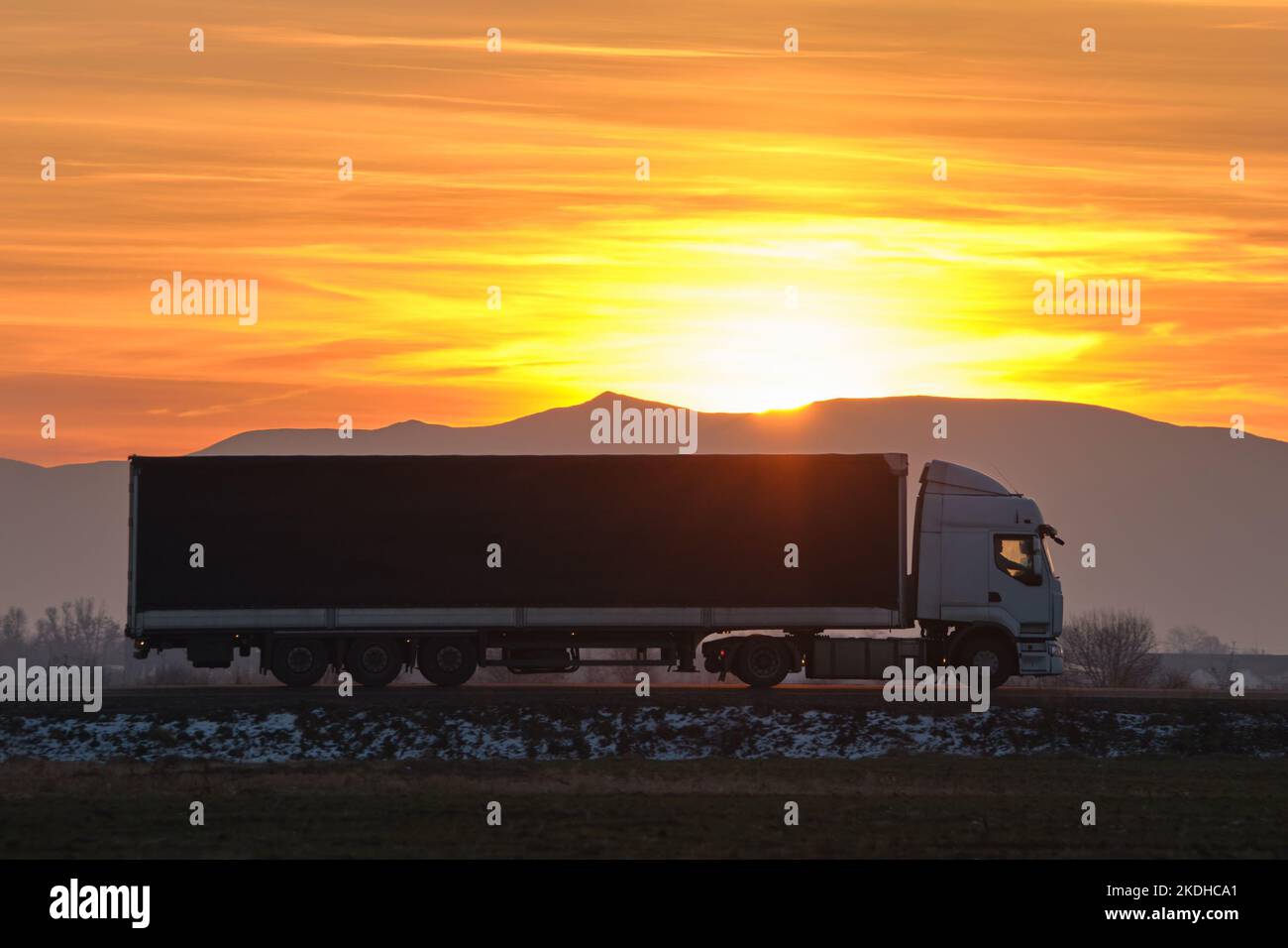 Semi-truck with cargo trailer driving on highway hauling goods in evening. Delivery ...