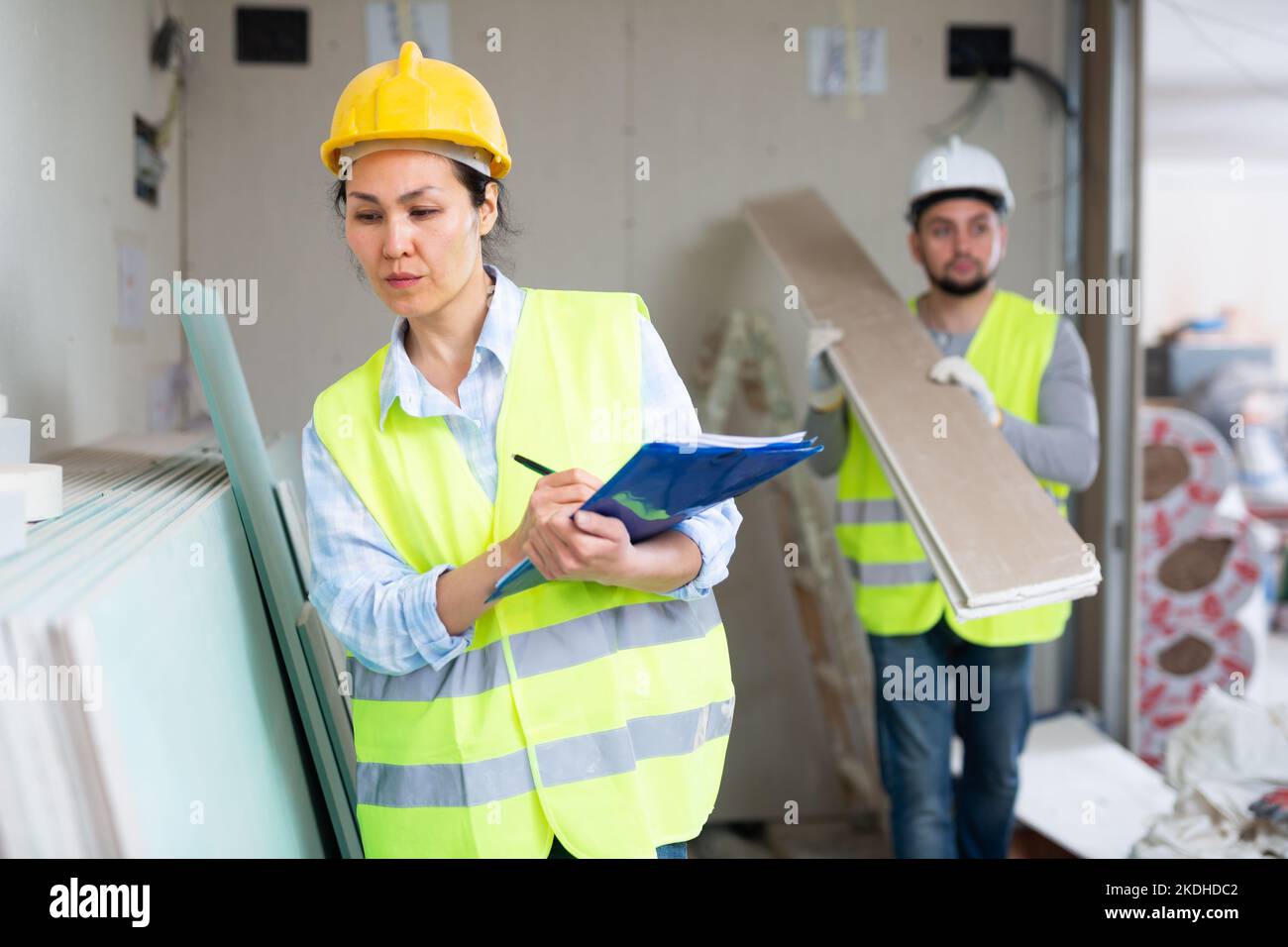 Female building inspector taking inventory of materials at construction ...