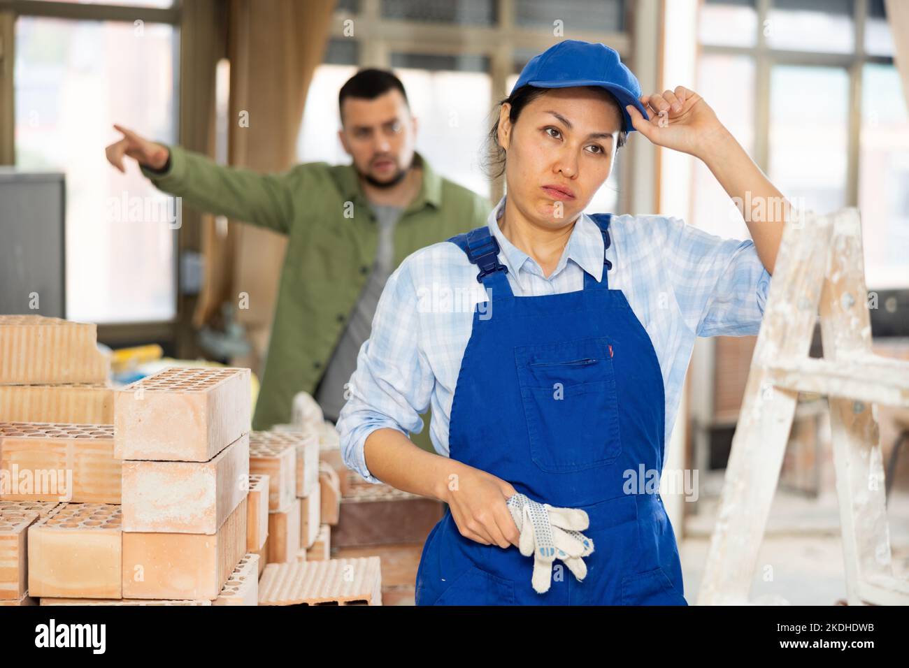 Puzzled female contractor in building under renovation with displeased ...