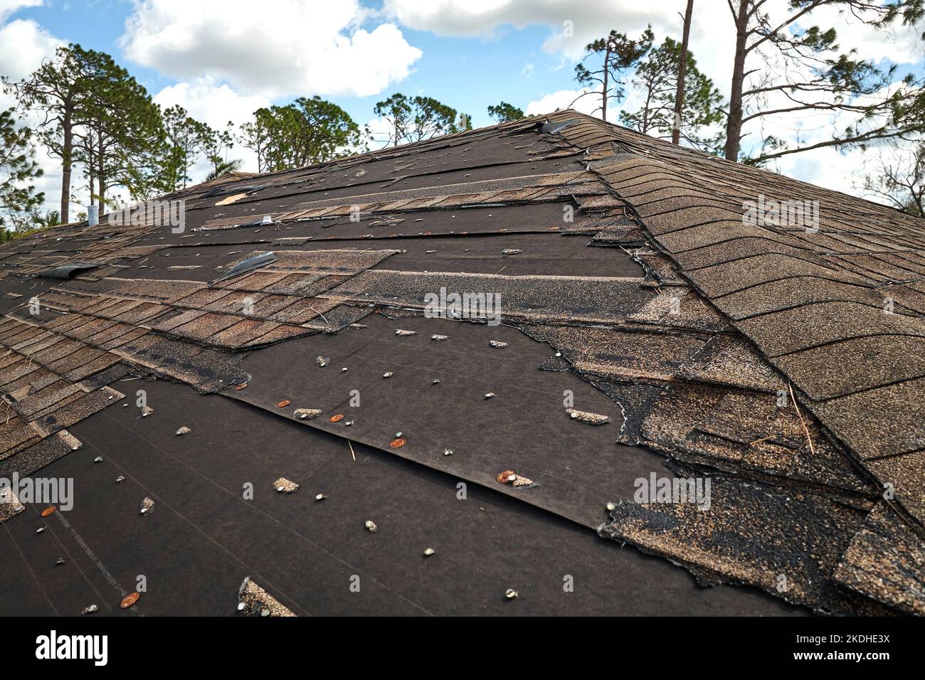 Wind damaged house roof with missing asphalt shingles after hurricane ...