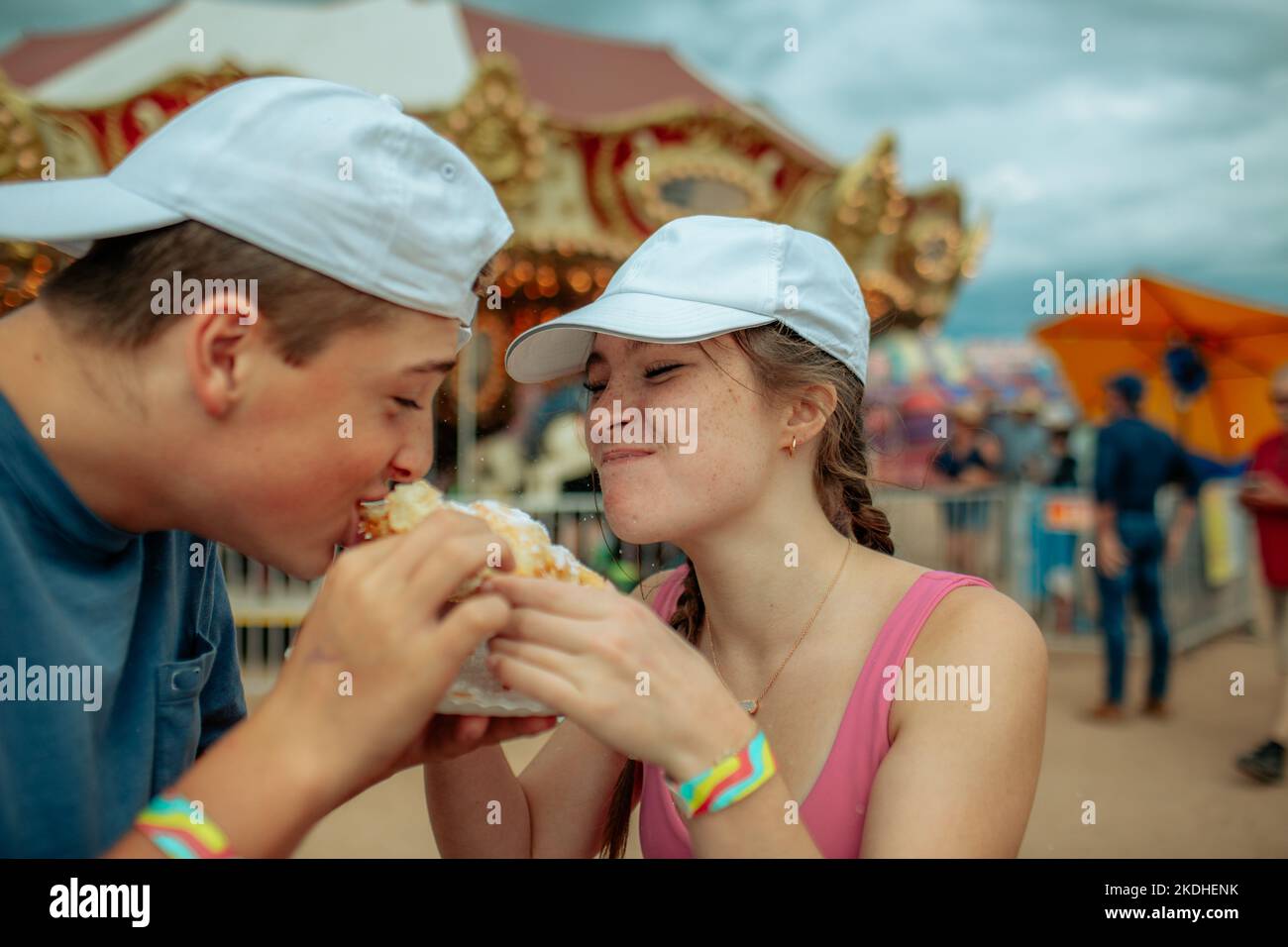 Teen kids at a carnival eating a funnel cake Stock Photo - Alamy