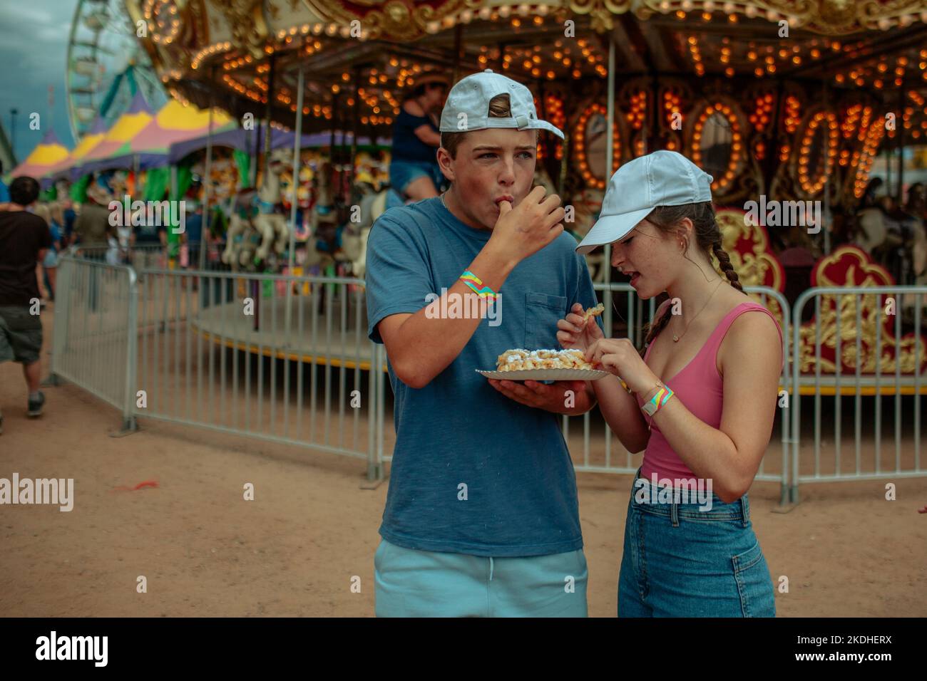 Two teenagers eating a snack at a carnival Stock Photo - Alamy