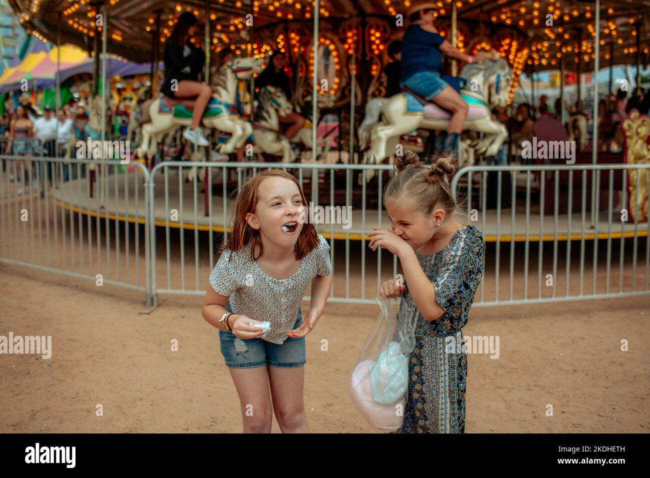 Goofy young girls eating cotton candy at a carnival Stock Photo - Alamy