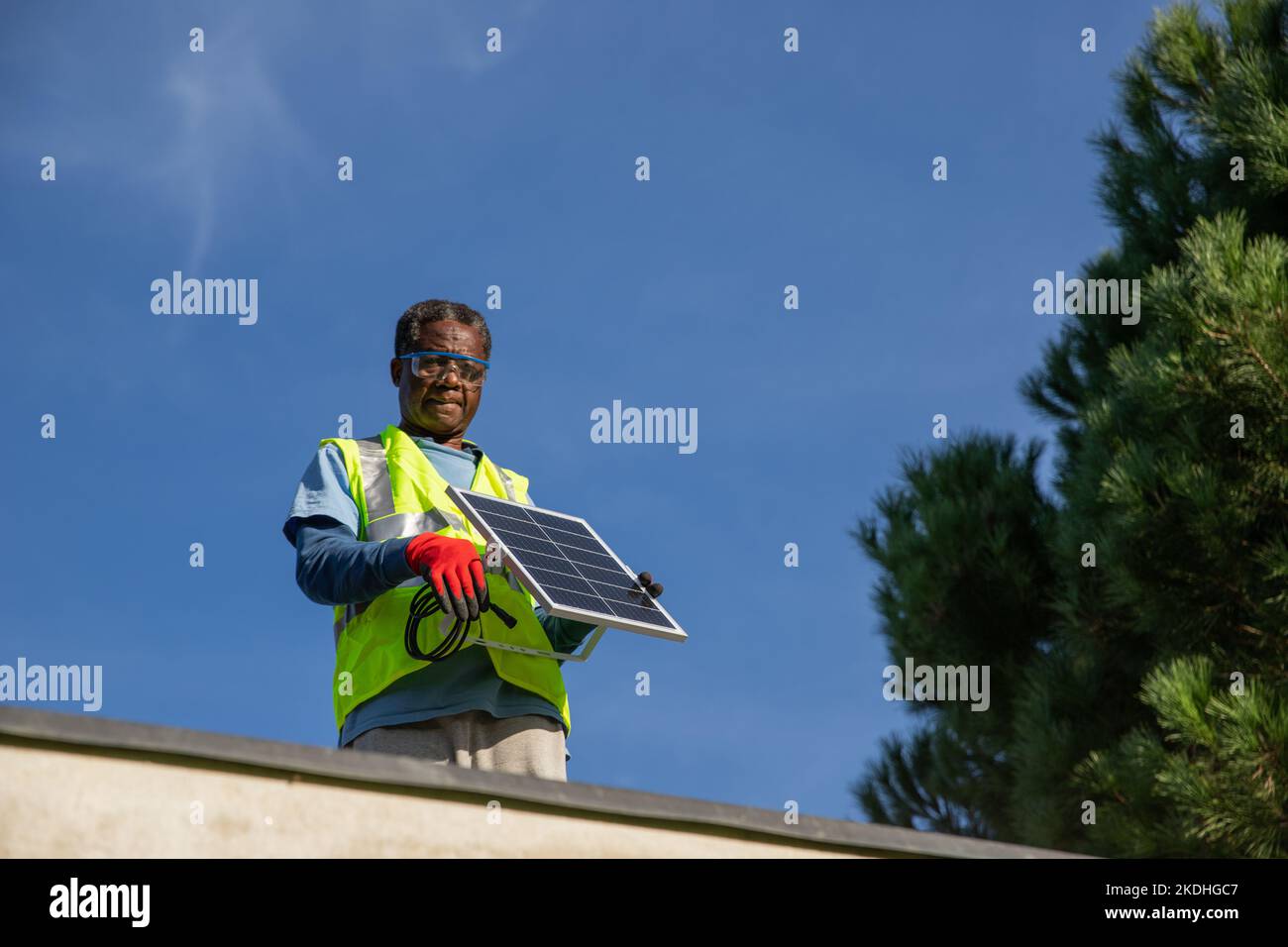 A worker installs a solar panel on a roof, renewable energy and energy ...