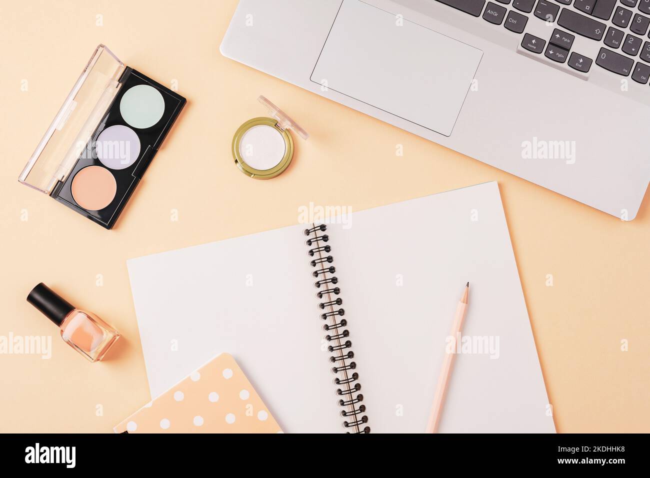 Desktop with notebook, laptop computer, pencil, makeup cosmetics ...