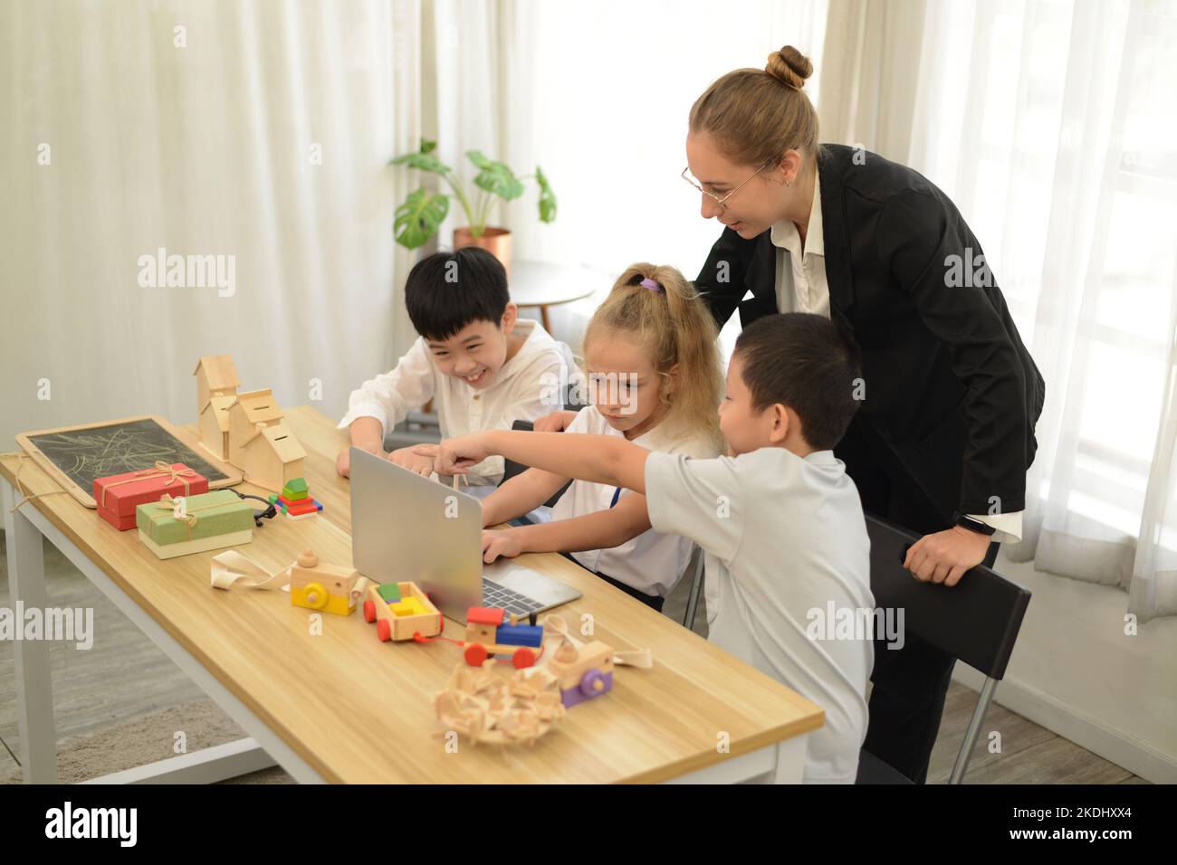 Teacher teaching her young students drawing toys or wood model on the ...