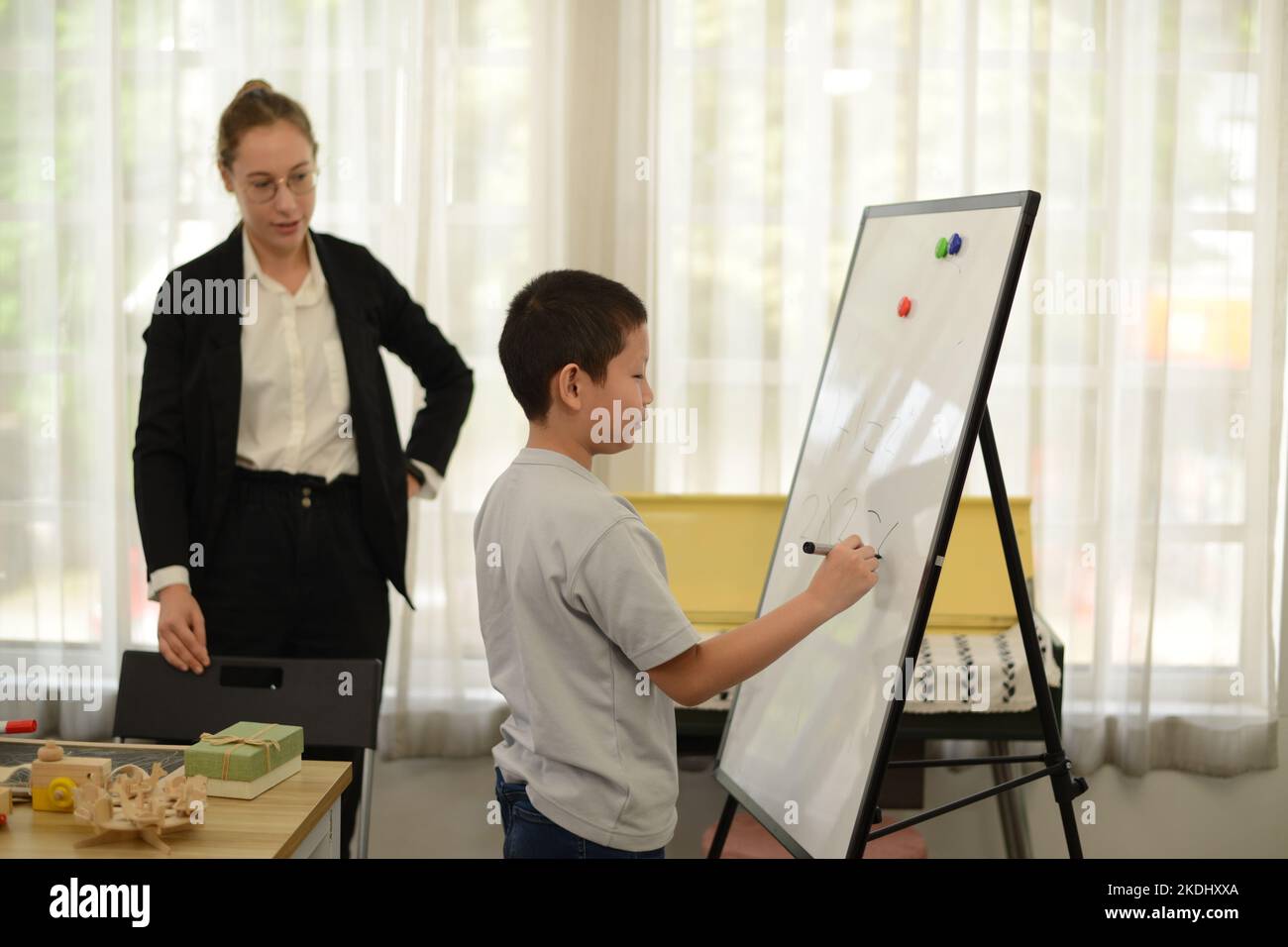 A teacher is teaching her little son how to draw with colorful pens in ...