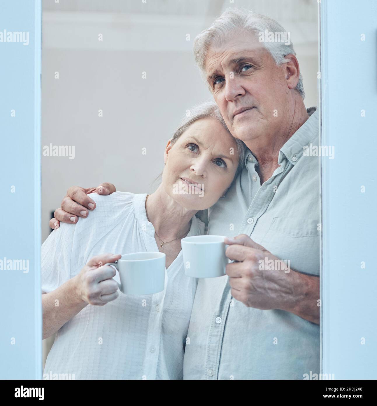 Love, coffee and senior couple at a window in their home, relax and hug ...