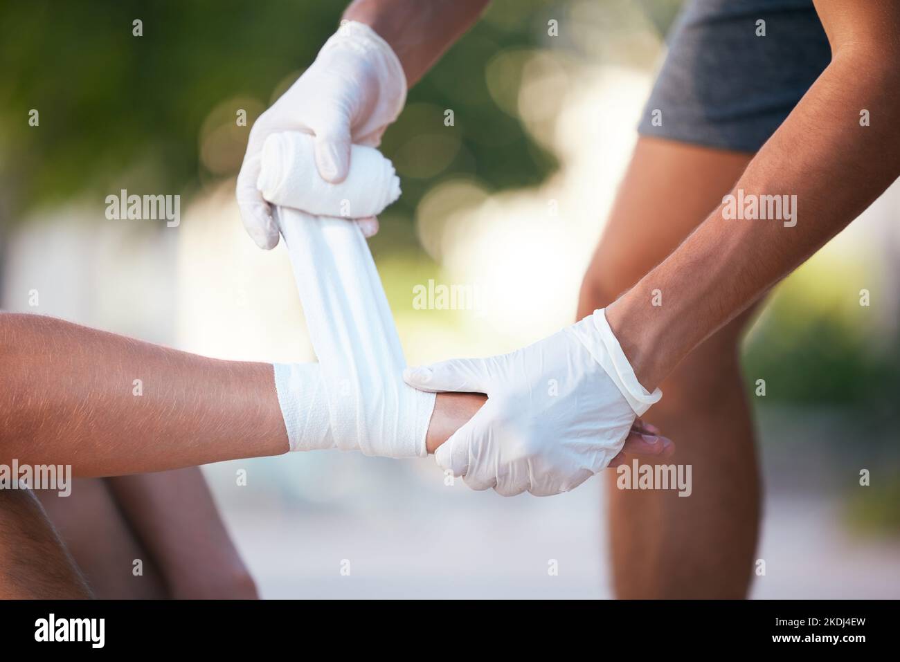 First aid, sports injury and bandage on wrist, man in park gets help ...