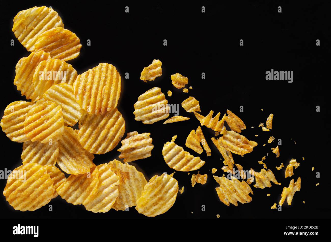 Crispy potato chips whole and broken on a black background, top view ...