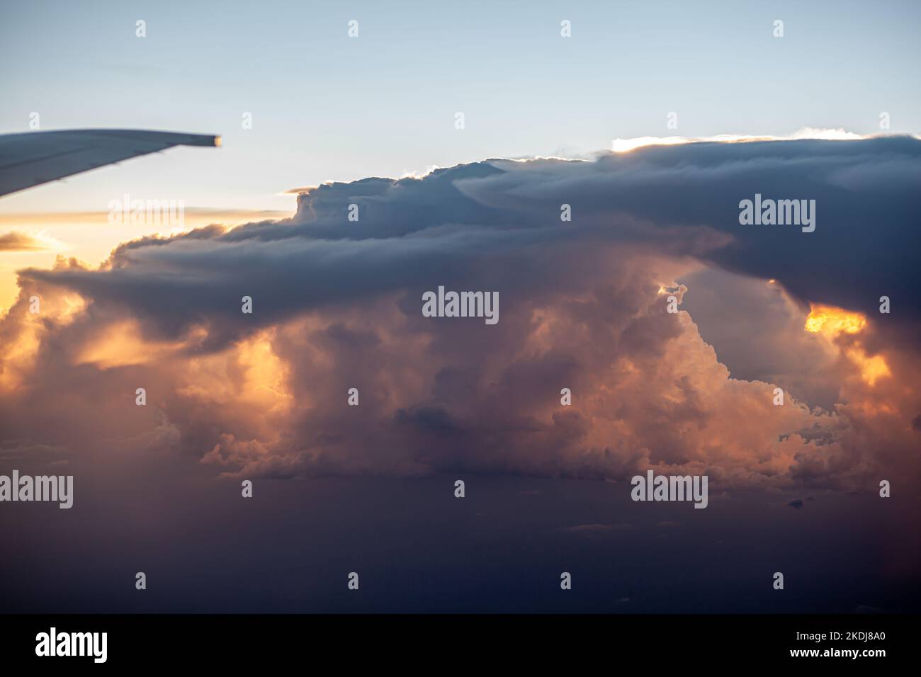 Airplane flight at sunset or dawn. Aircraft's wing and land seen through the illuminator. View ...