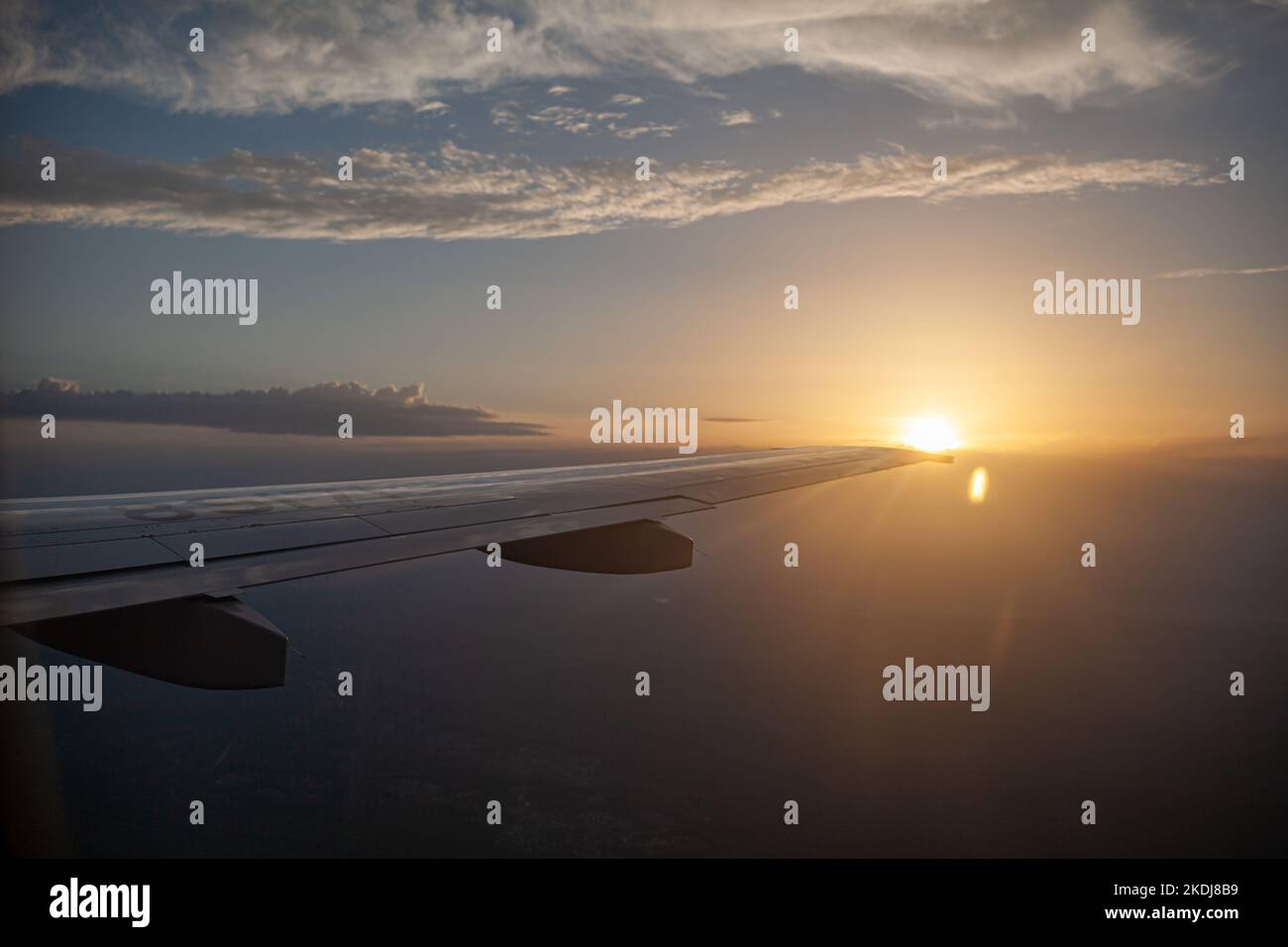 Airplane flight at sunset or dawn. Aircraft's wing and land seen ...
