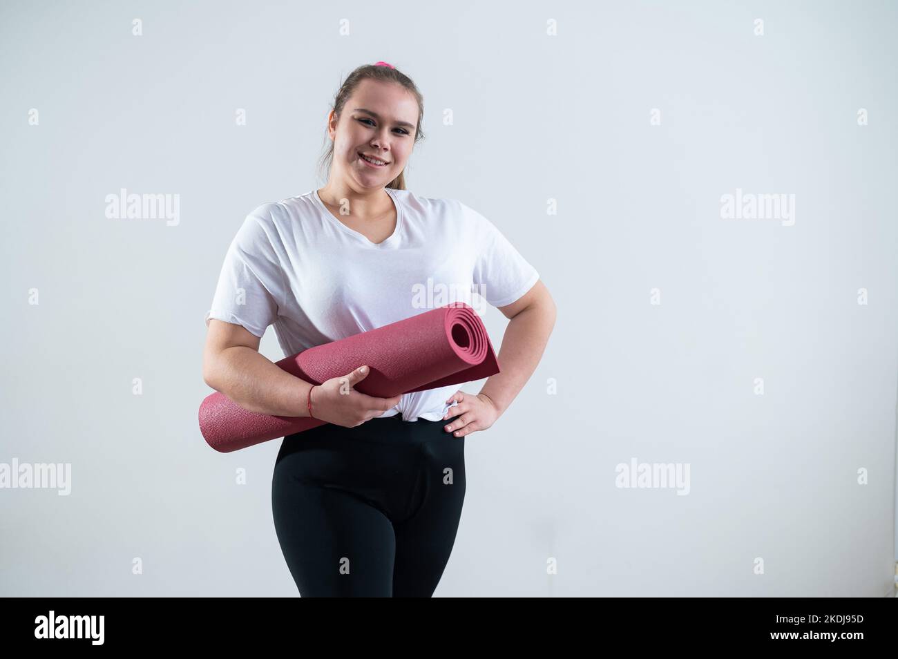 Young fat caucasian woman holding a sport mat. Charming plus size model ...