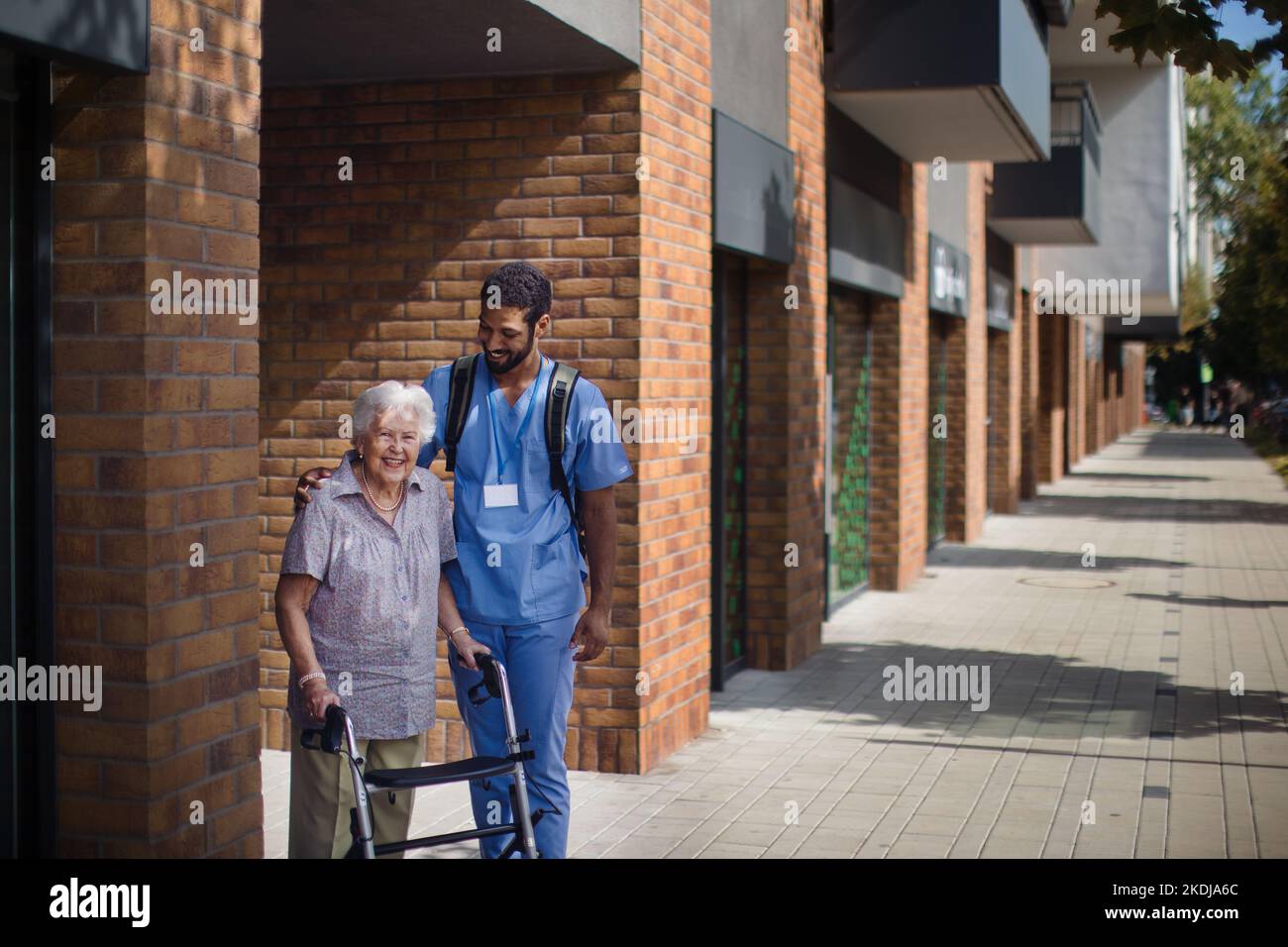 Caregiver walking with senior woman client in front of nurishing home ...