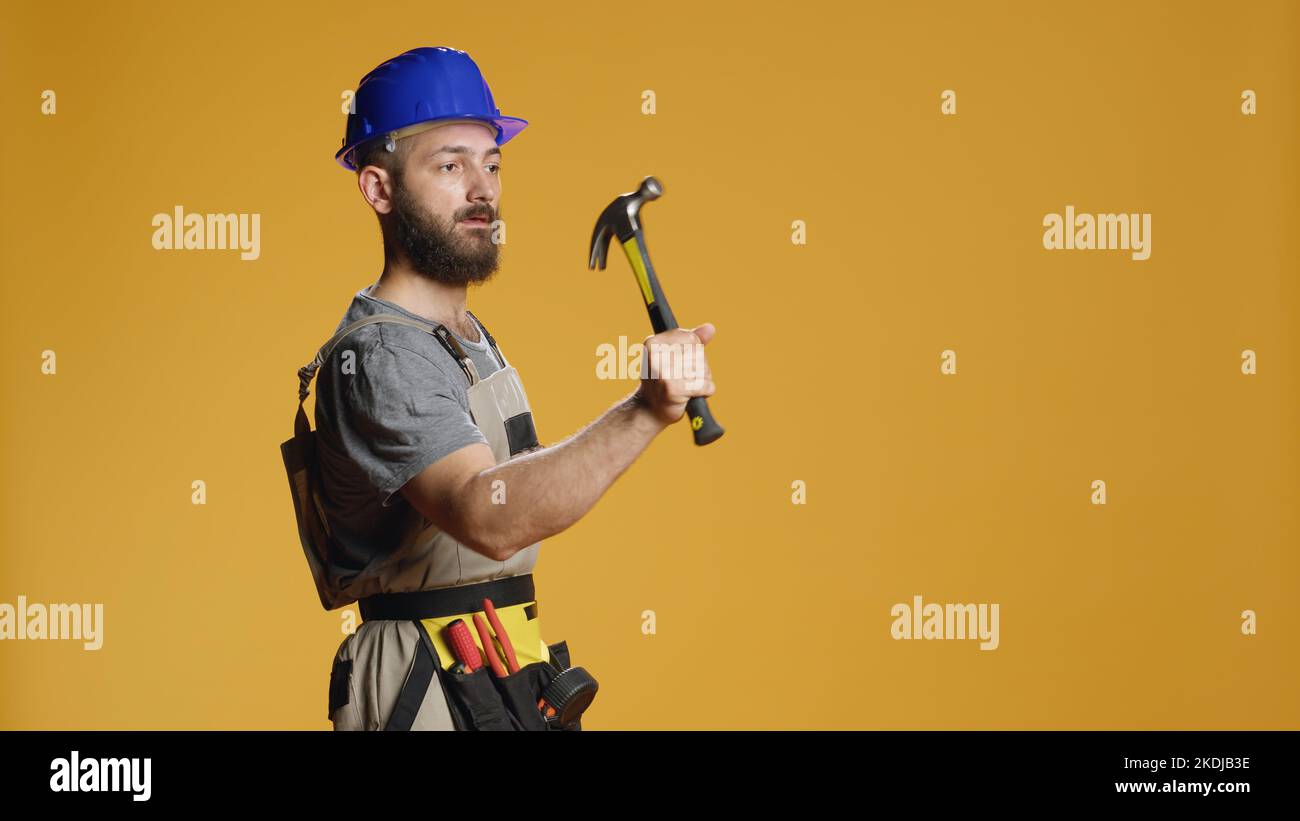 Construction worker using manual hammer to hit nails in wall, working ...